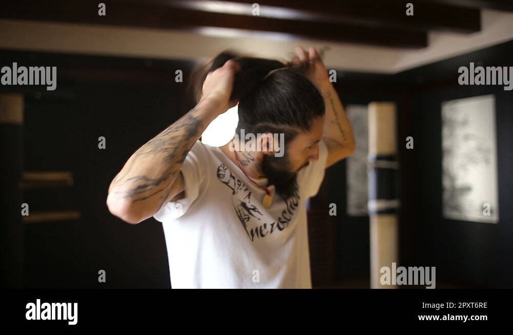 A Tai chi fighter tie his hair in the tail in the training hall Stock ...