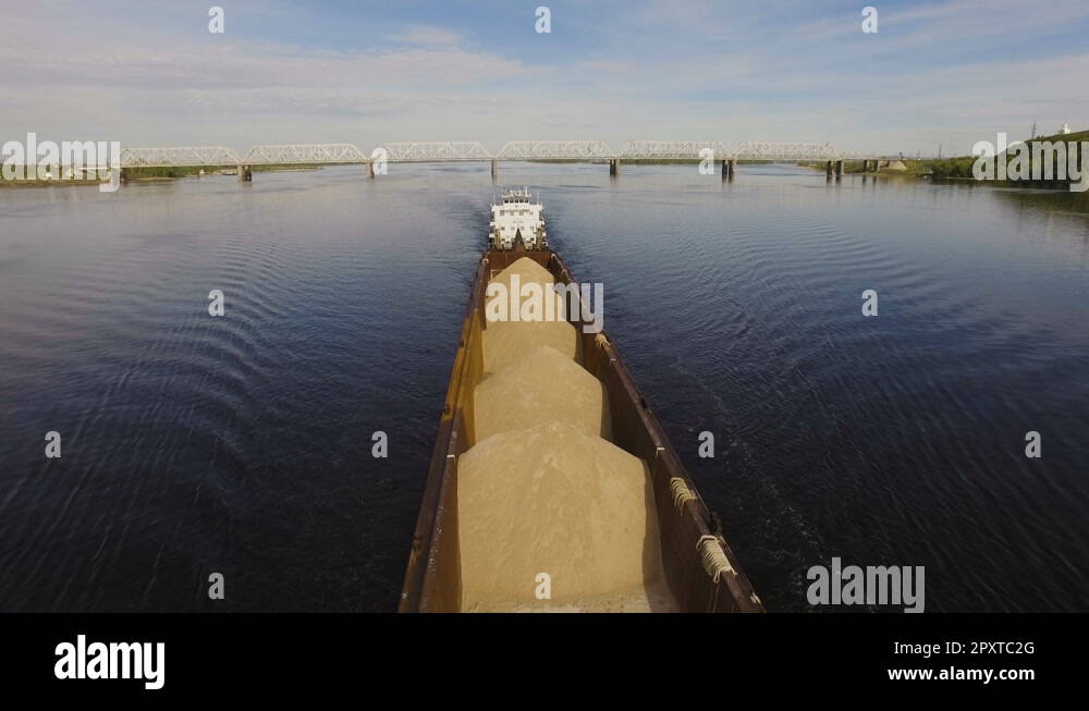 barge loaded with sand and gravel floats on the wide river on the ...