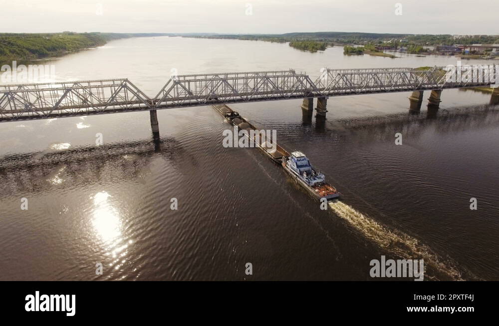 barge with sand and gravel sails under the railroad bridge across the ...