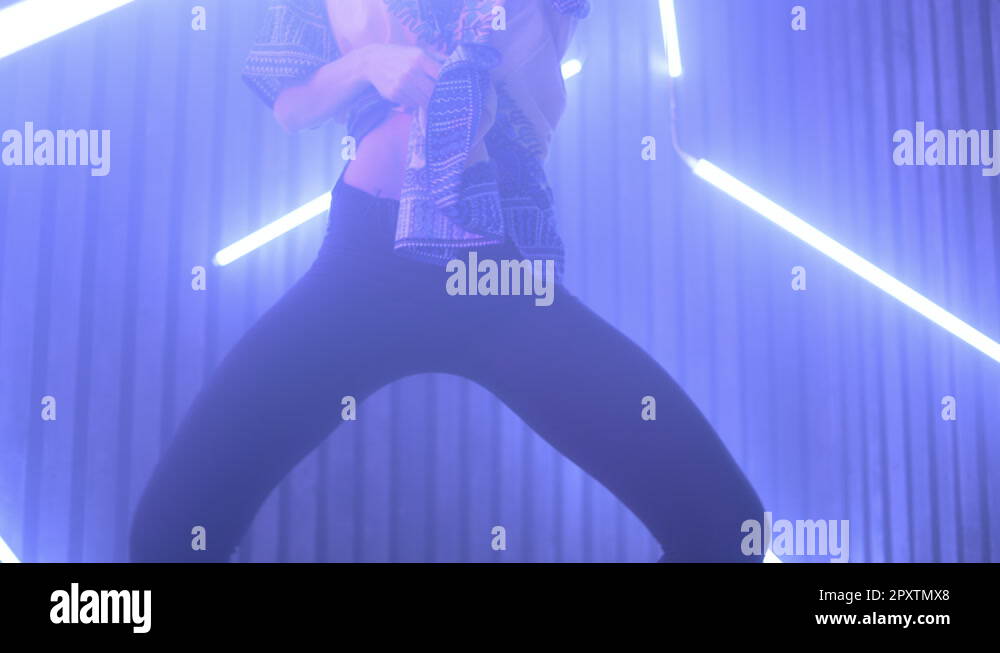 Girl dancing on fluorescent light background. Sexy woman dancing at ...