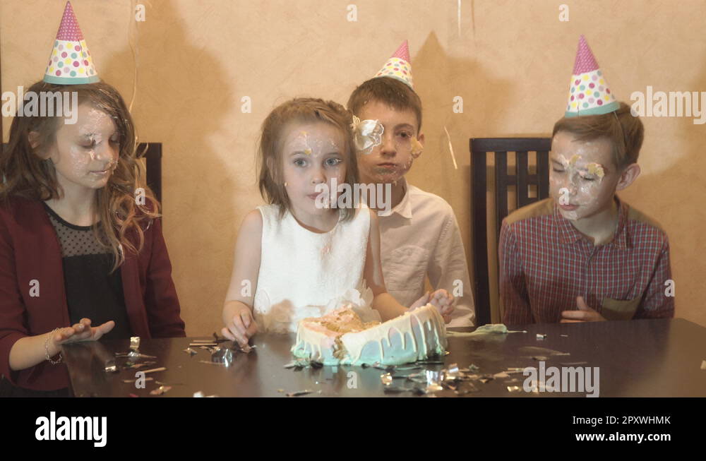 carefree children at a birthday party. face of little girl in cake and ...