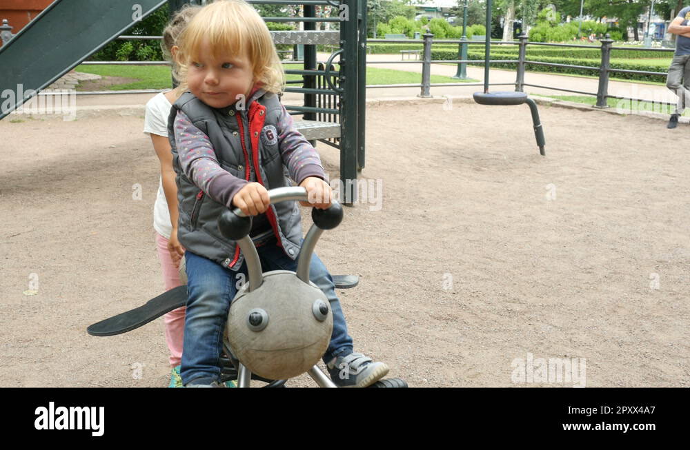 Two children walking on playground and swinging on big swing set Stock ...