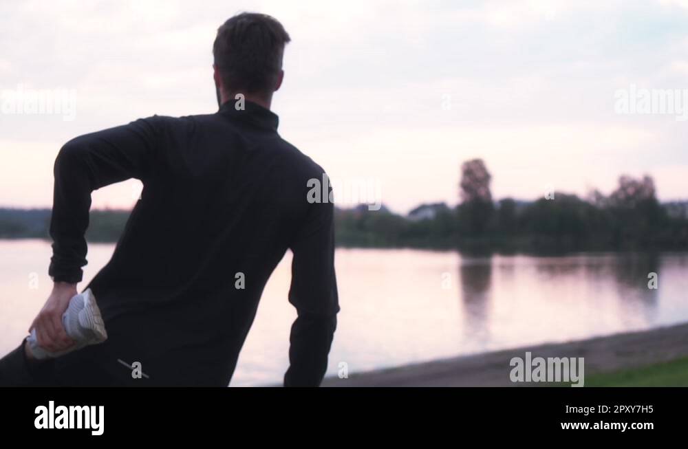 Slow motion man stretching legs at beautiful lake. Back view free male ...