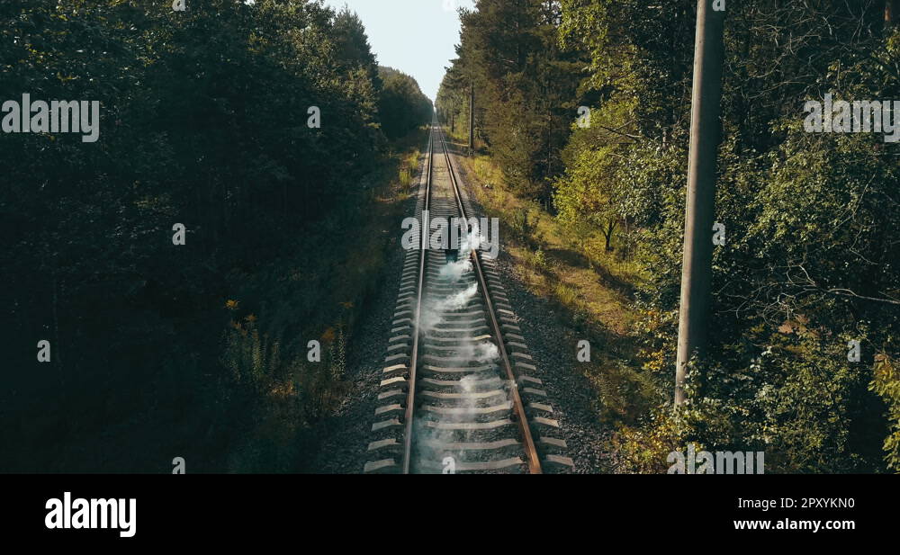 Man running on train tracks with smoke bomb. Drone back view. Runner ...