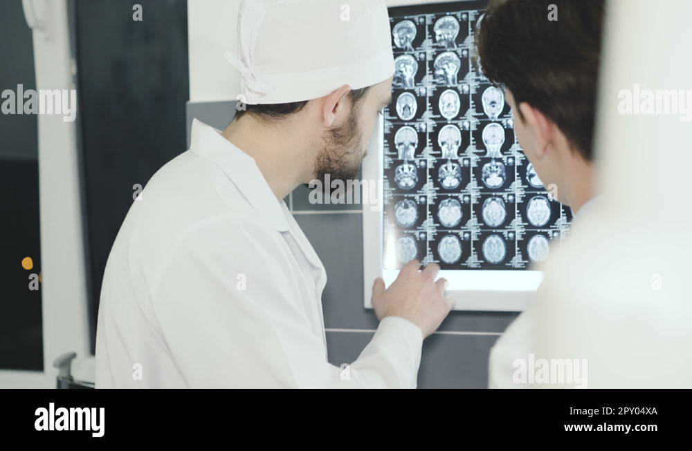 Back view. Two doctors advising at mri display in hospital room. 4K ...