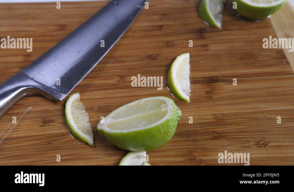Sliced fresh half lime cut into segments with sharp knife blade using ...