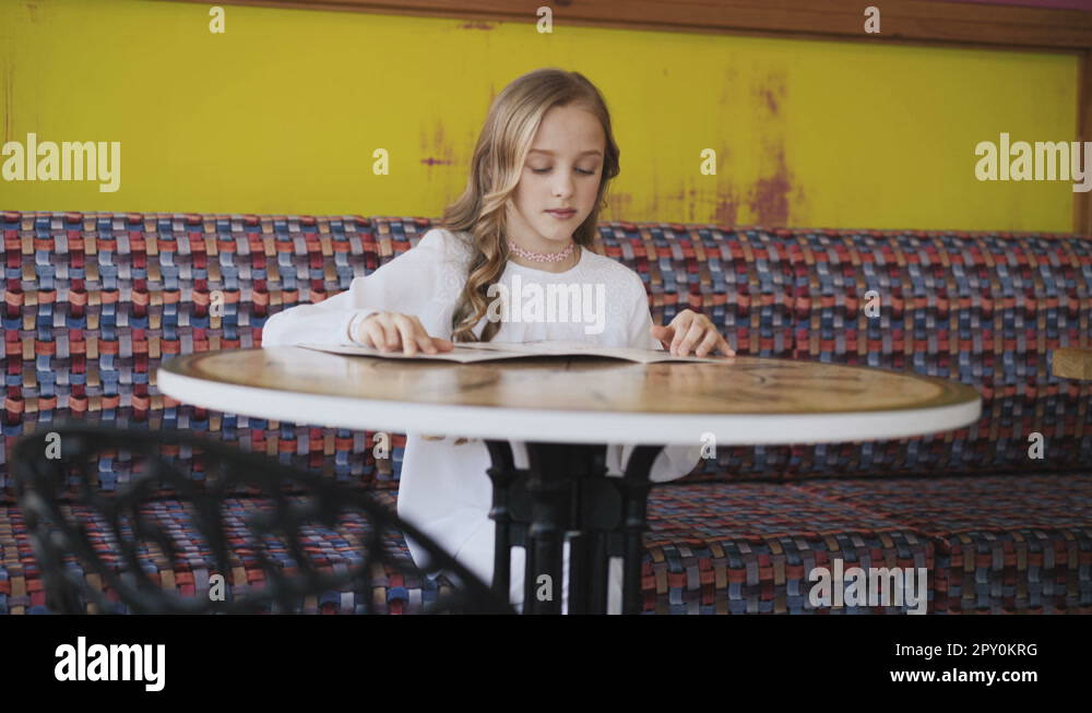 Pretty, smiling and young girl reading the menu in cafe. 4K Stock Video ...