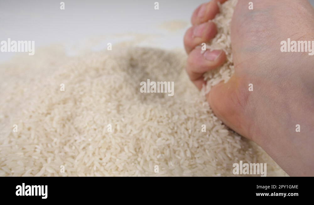 Slow motion white rice with mans hand grabbing and pouring onto a white ...