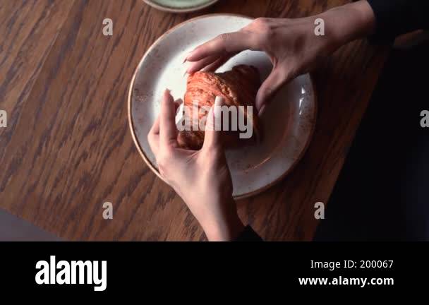 Female person cracks freshly baked croissant placed on white stylish ...