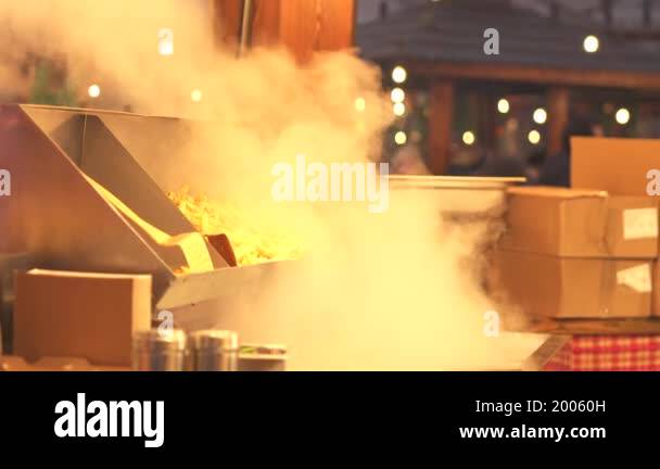 Freshly cooked French fries steam in a food stall kitchen, creating a ...