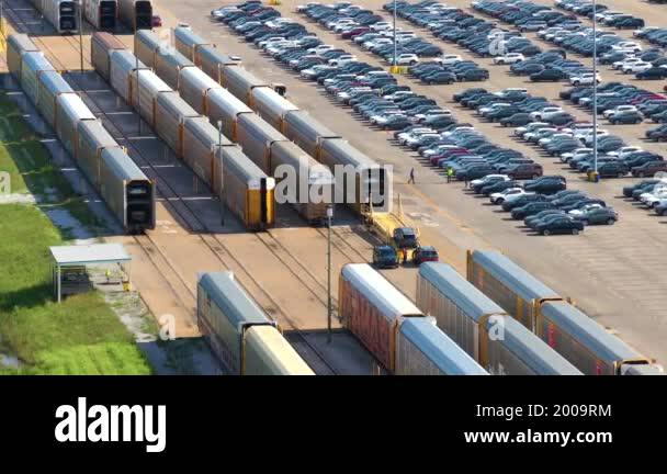 Cargo train transporting cars. Factory parking lot with many brand new ...