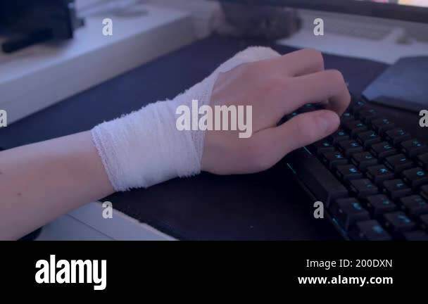 A hand that is carefully wrapped in white bandages is typing on a ...