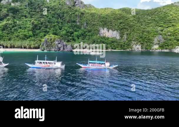 Traditional tropical outrigger boats float on crystal-clear waters near ...