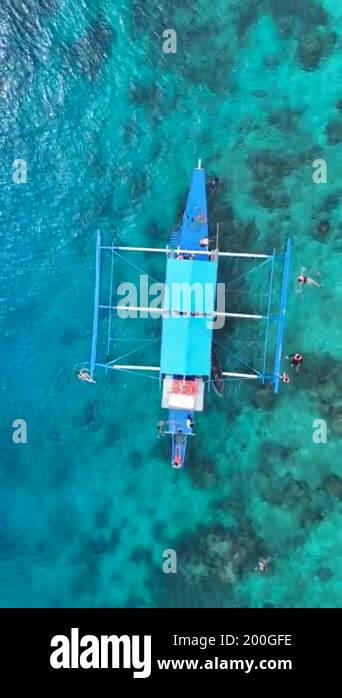 An aerial view of a traditional outrigger boat anchored in vibrant ...