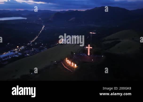 Stunning aerial footage showcasing a glowing cross on a hilltop during twilight, surrounded by ...