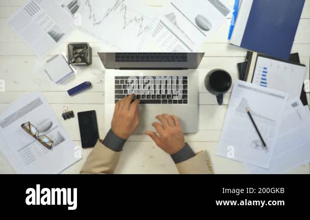 Male hands of manager typing text on laptop keyboard at white desk. Top ...