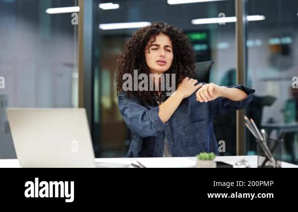 Stressed businesswoman with curly hair massages shoulder, suffering ...