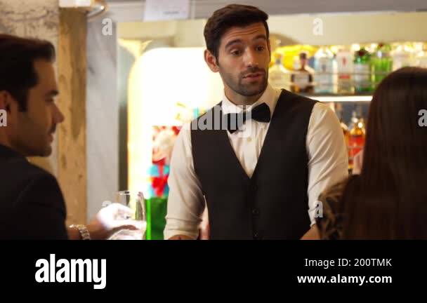 Good looking bartender serving welcome drink with friendly conversation ...
