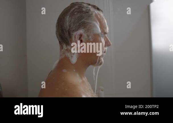 Man washing hair under shower, enjoying a refreshing cleanse. Water ...