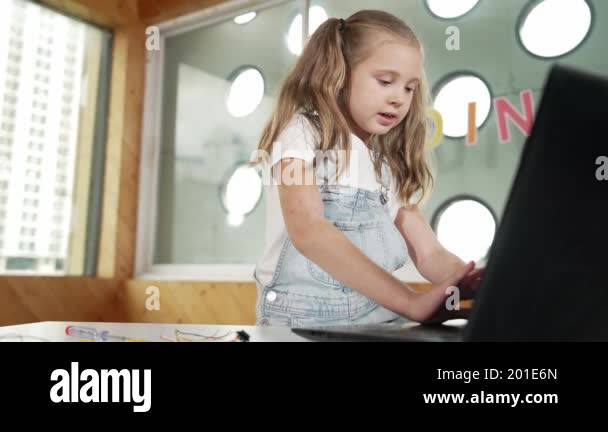 Cute girl using laptop programing software while looking at camera with ...