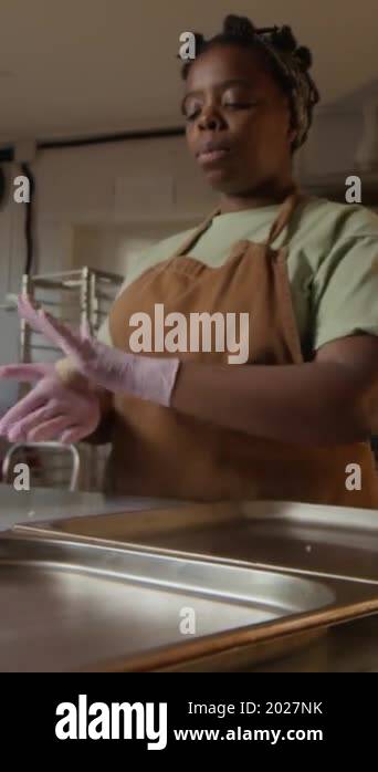 Vertical low angle medium shot of African American female baker in ...