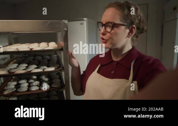 POV shot of Caucasian female baker wearing beige apron and maroon shirt ...