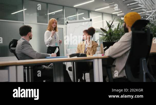 Young woman stands at whiteboard gesticulating at project presentation ...