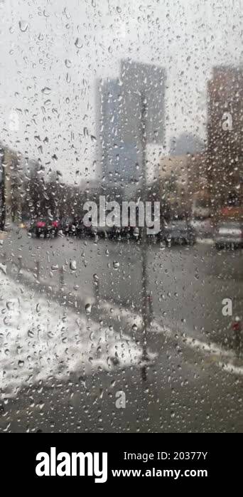 rain outside, cars drive down the street in the rain behind glass with ...
