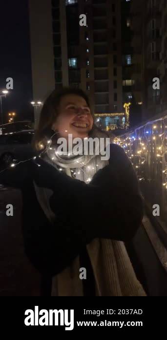 a dreamy woman stands outside near a high-rise building, decorated with ...