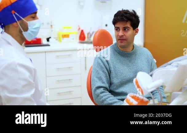 Dentist wearing a mask and surgical cap shakes hands with a smiling ...