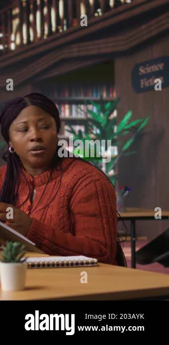 Vertical Video Black tutor mentoring schoolgirl in a school library ...