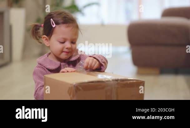 Cute little child girl opens parcel cardboard box at home Stock Video ...