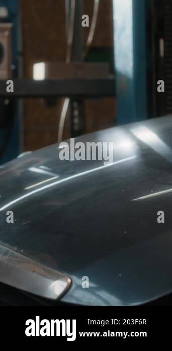 Vertical shot of male mechanic inspecting car bonnet using dipstick to ...