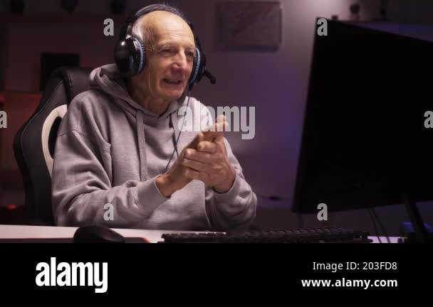 Elderly retired man streamer playing video game with good expression at ...