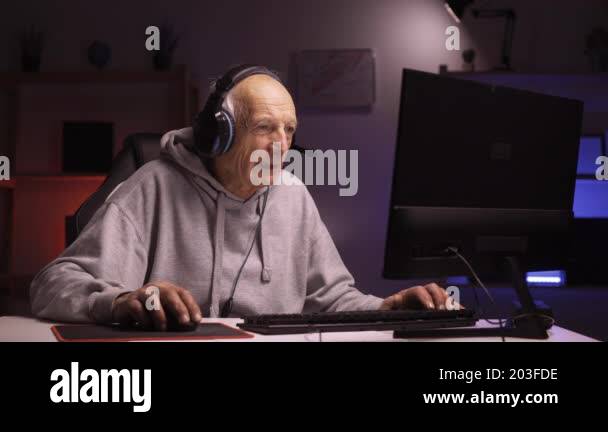 Elderly pensioner man playing online games using PC gaming setup having ...