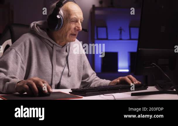 elderly pensioner man playing online games using pc gaming setup having ...