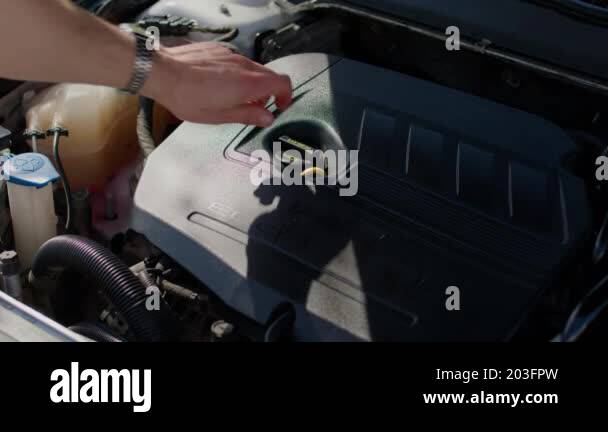Mechanic opens oil filler cap of car to check fluid condition. Specialist inspects vehicle ...