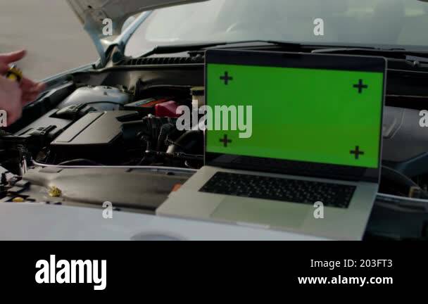 Technician works with tool and repairs car using laptop. Man works on fixing malfunction of ...
