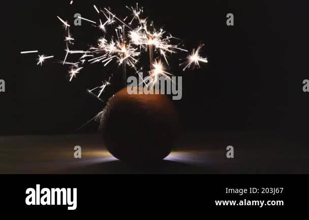 High-quality footage of a sparkler burning on an orange in the dark ...