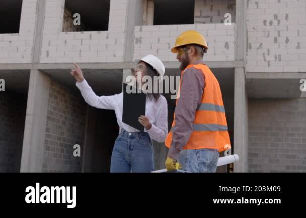 Female architect pointing at something while discussing with ...