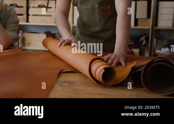 Unrecognizable master craftsman in apron and his assistant rolling out ...