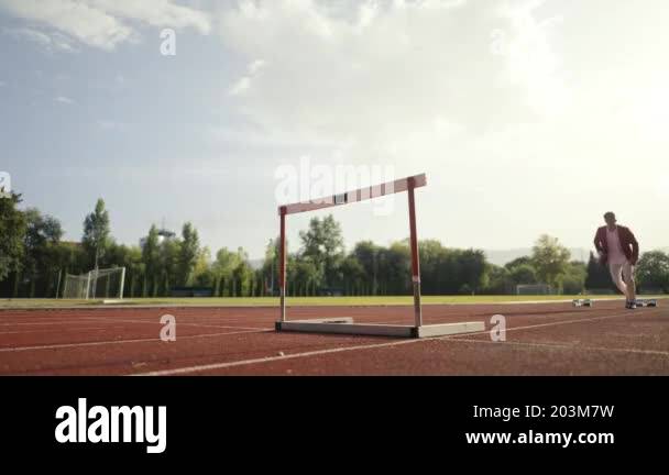 Businessman jumping a hurdle while running on the athletics racing ...