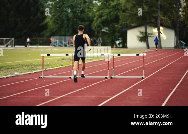 Strong Male Athlete is Running Towards an Obstacle, Hurdling, Jumping ...