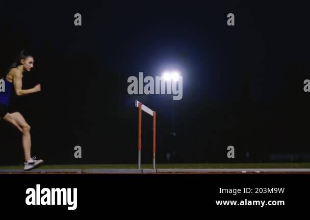 Female Athlete is Running Towards an Obstacle, Hurdling, Jumping Over ...
