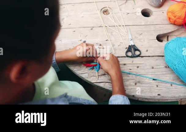 Close-up of a person crafting with colorful yarn outdoors The serene ...
