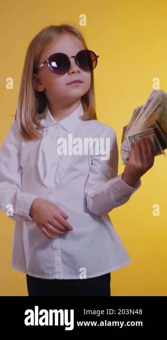 Vertical, a confident smiling child holds money dollars in her hands ...