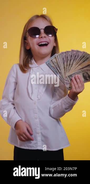 Vertical, a confident smiling child holds money dollars in her hands ...