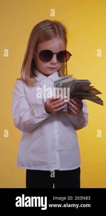 Vertical, a confident smiling child holds money dollars in her hands ...