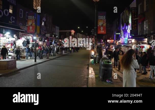 Camden Town's bustling streets at night feature bright neon signs ...