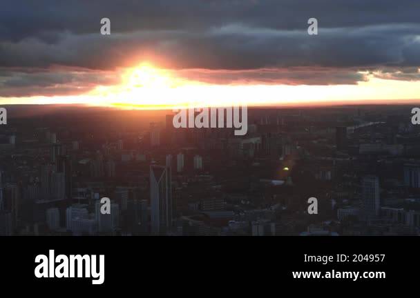 The sun sets behind clouds over London's skyline, silhouetting ...